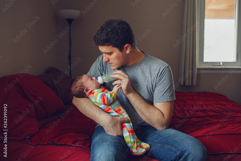 Young Caucasian father feeding newborn baby son daughter with milk ...