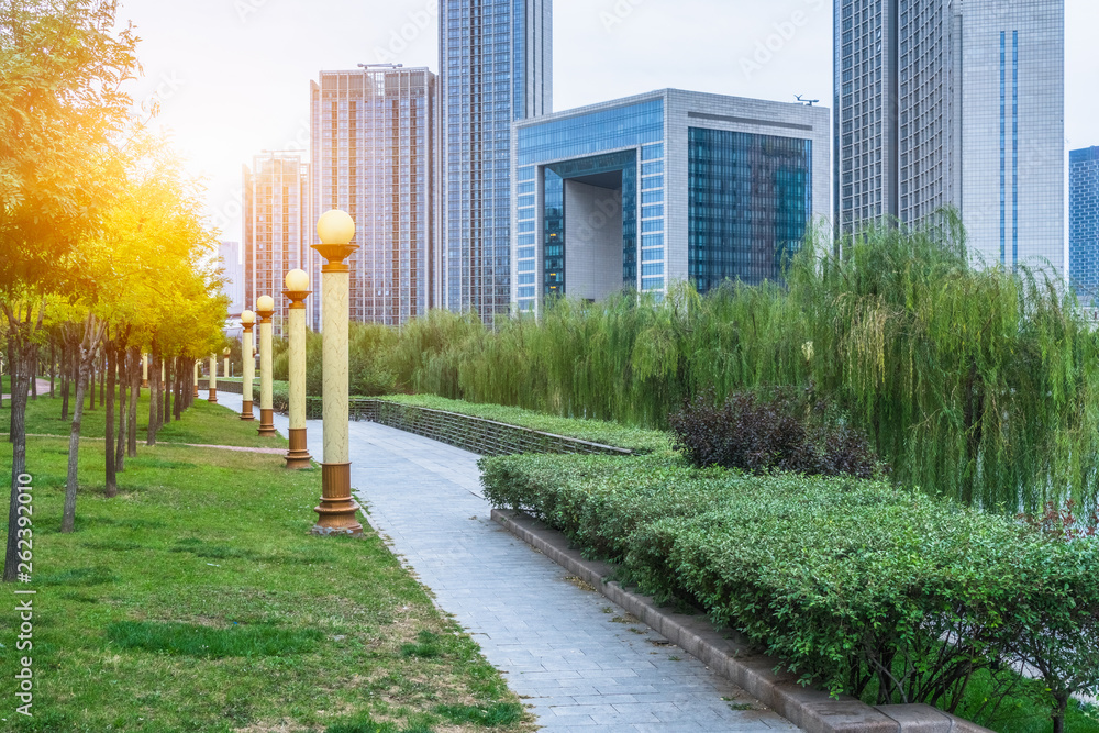 park pedestrian walkway and modern skyscrapers, dalian city, china ...