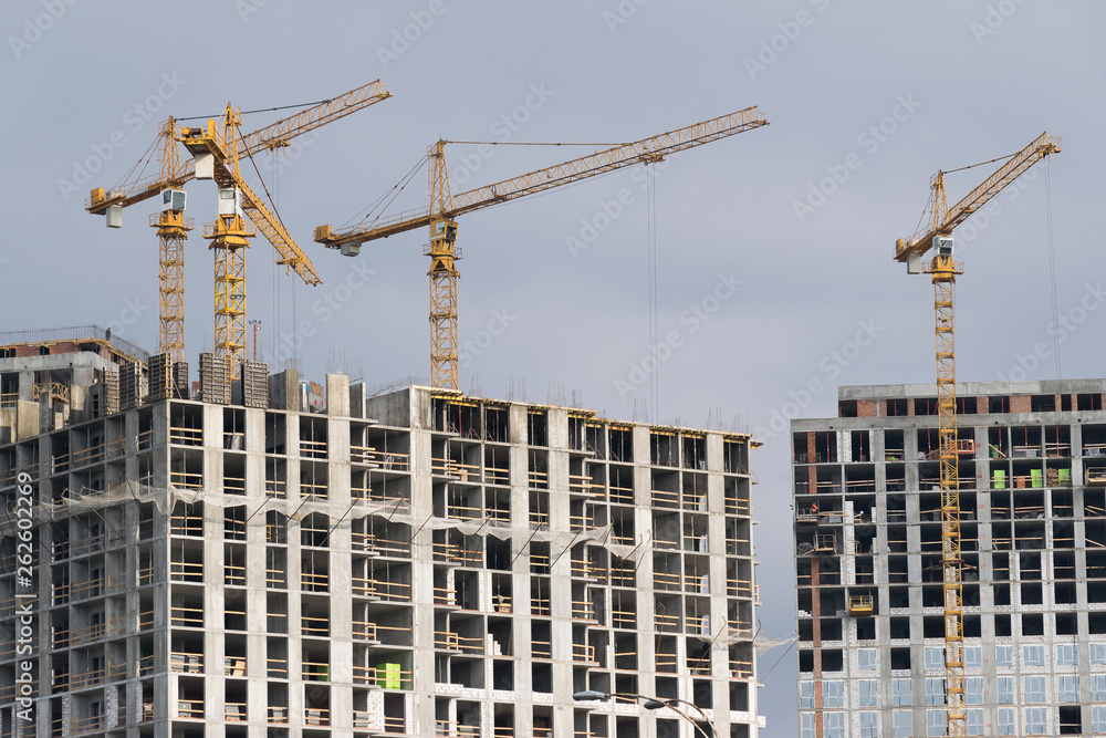 High-rise building crane with a long arrow of yellow color against the ...