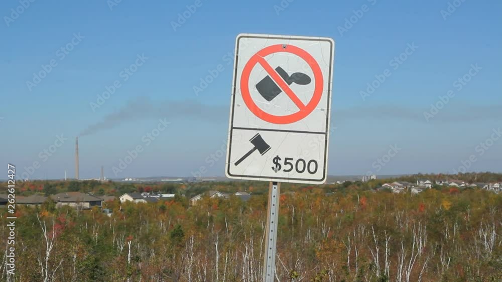 No littering sign showing possible $500 fine. Giant chimney spewing ...