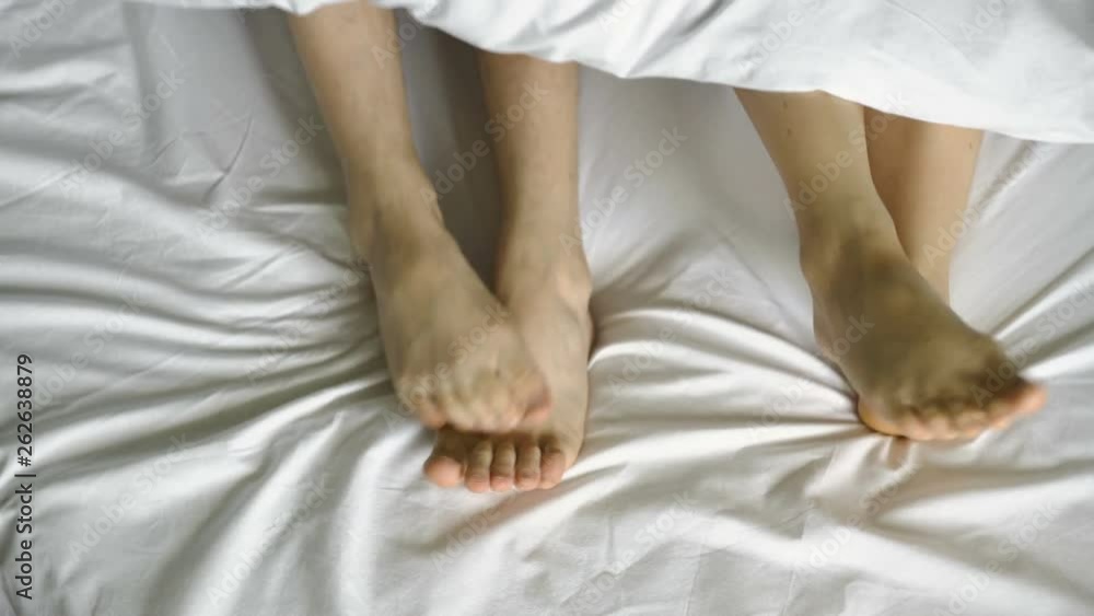 couple in bed making love. male and female legs top view, white linens ...