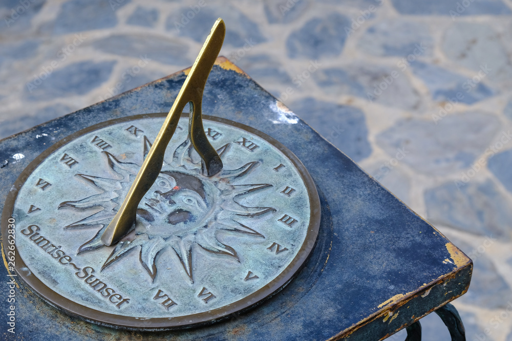 Close-up of a brass sundial mounted on a stone plinth in a garden ...