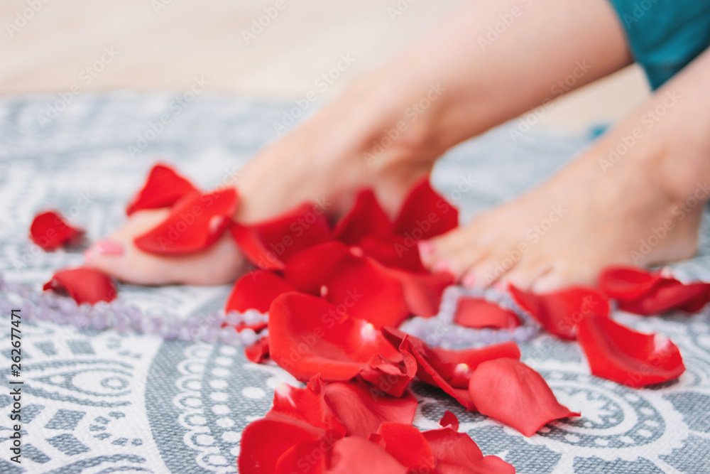 Beautiful female tanned legs with pink pedicure among rose petals ...