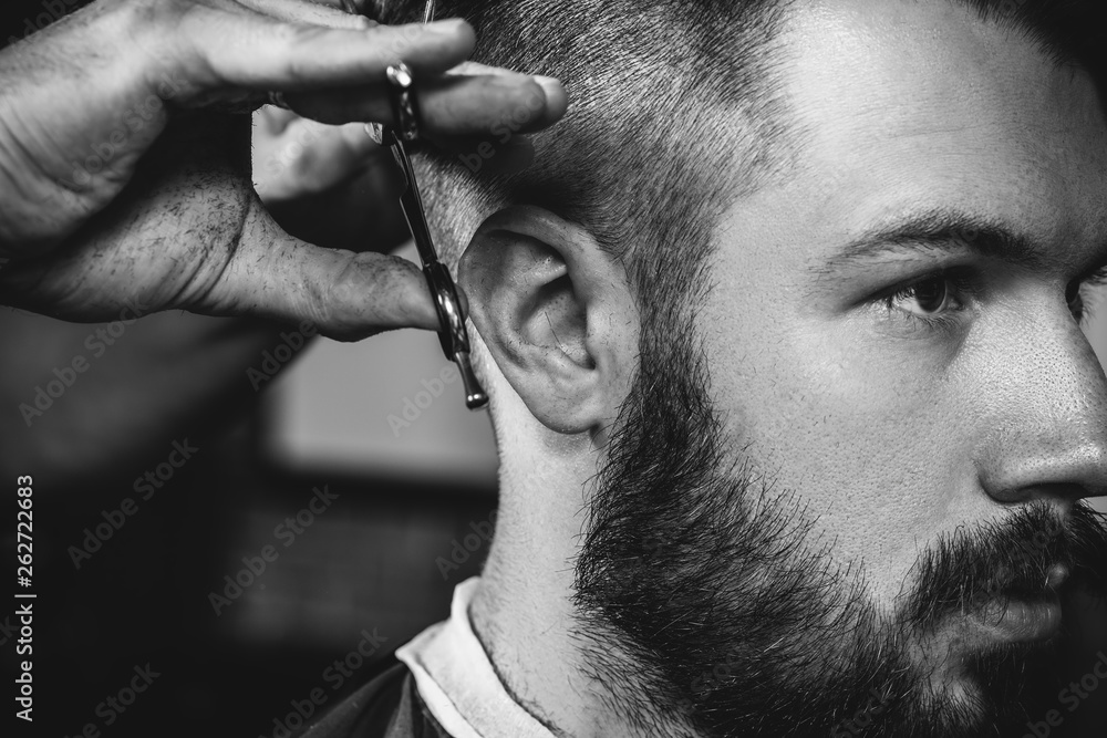 Young Handsome Barber Making Haircut For Attractive Bearded Man At