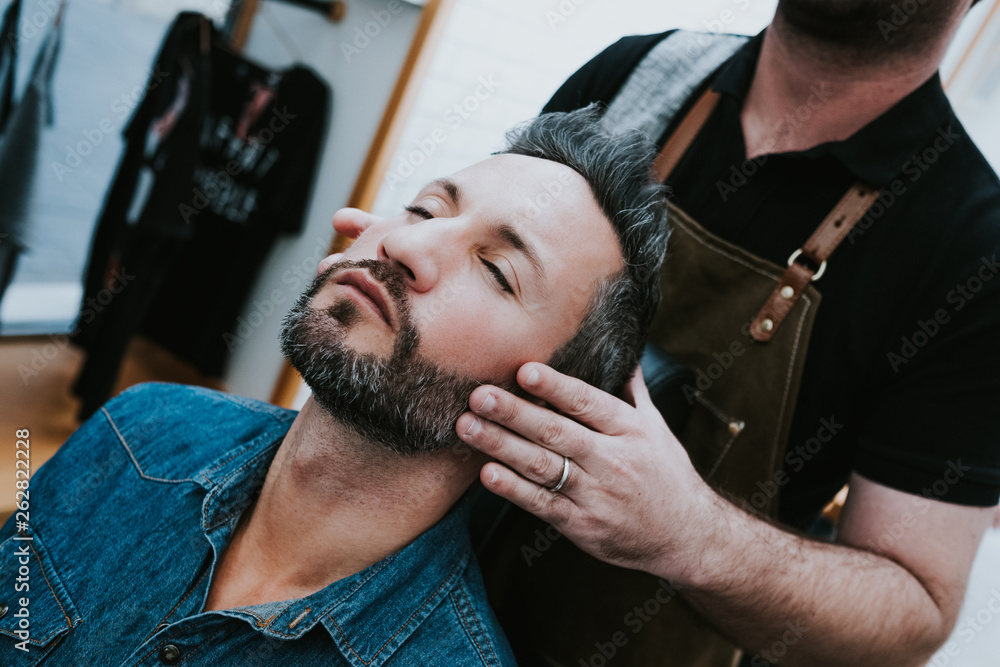 Crop barber doing face massage to handsome stylish male with closed ...