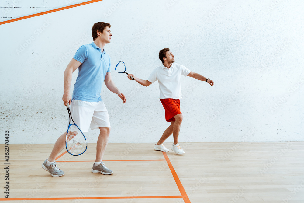 Full length view of two sportsmen playing squash in four-walled court ...