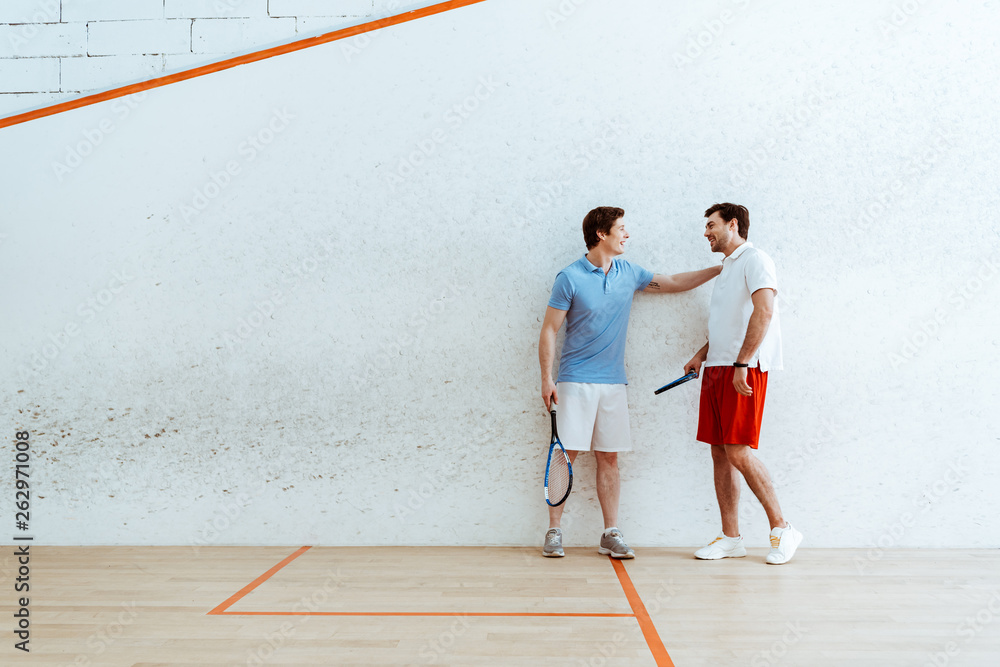Full length view of squash player putting hand on shoulder of friend ...
