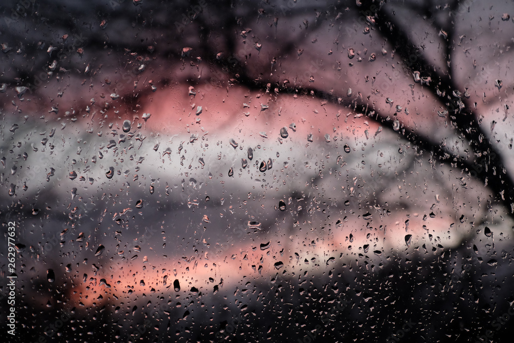Blurry sunset in the rain as seen through a wet glass with water ...