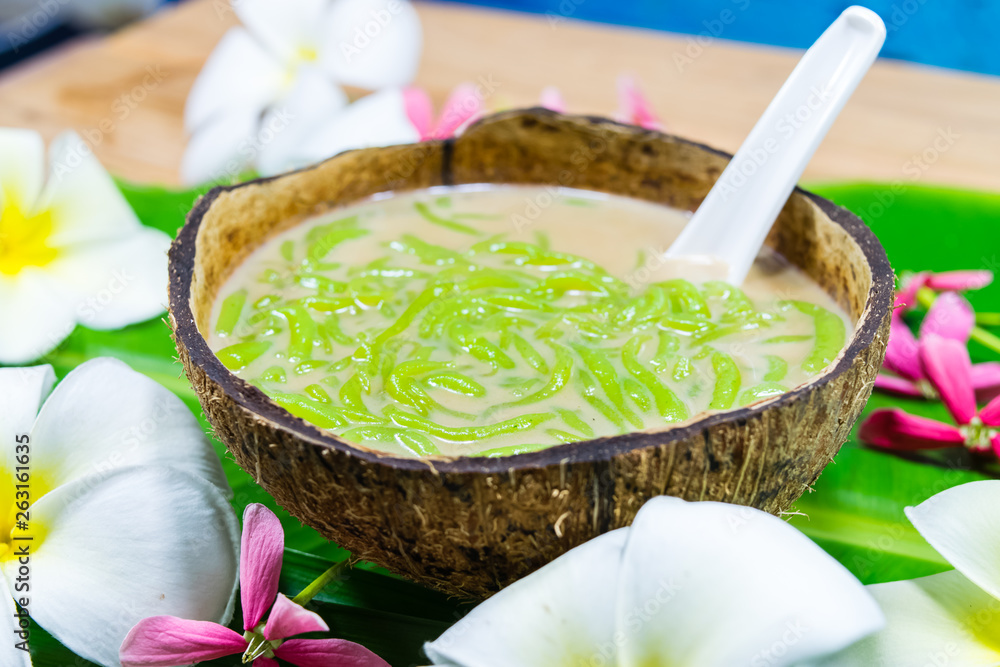 traditional thai dessert (Lot Chong) in a coconut shell with flowers on ...