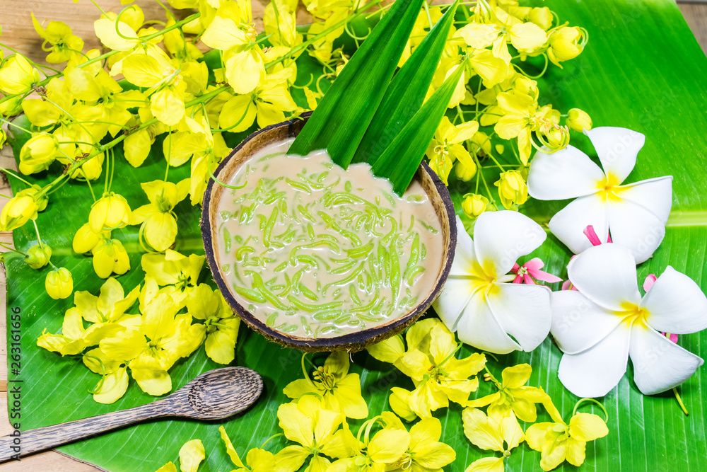 traditional thai dessert (Lot Chong) in a coconut shell with flowers on ...