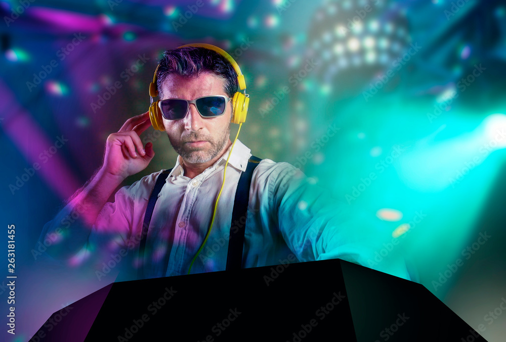 young attractive and cool DJ in shirt and suspenders remixing music at ...