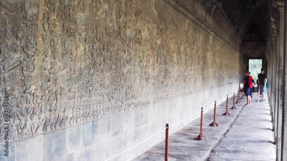 Murals on stone wall in gallery showing great battle in Angkor Wat ...
