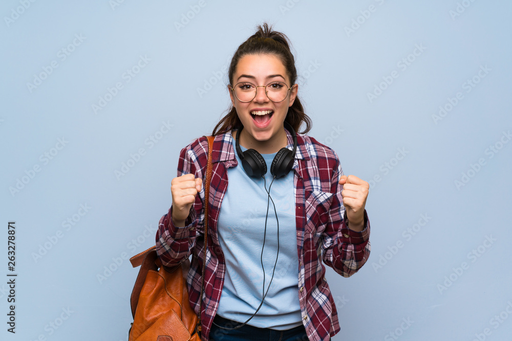 Teenager student girl over isolated blue wall celebrating a victory in ...