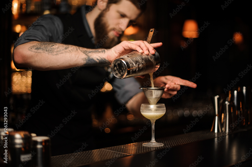 Bartender prepares an alcohol cocktail using shaker and sieve Stock ...