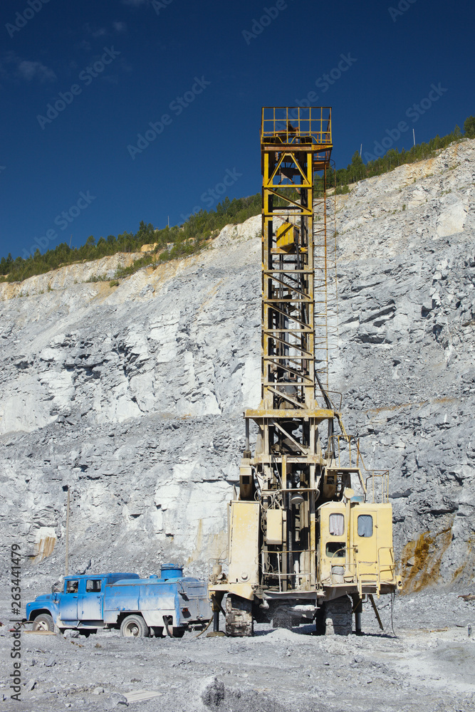 Quarry drilling machine in the quarry. Refilling with water from a tank ...