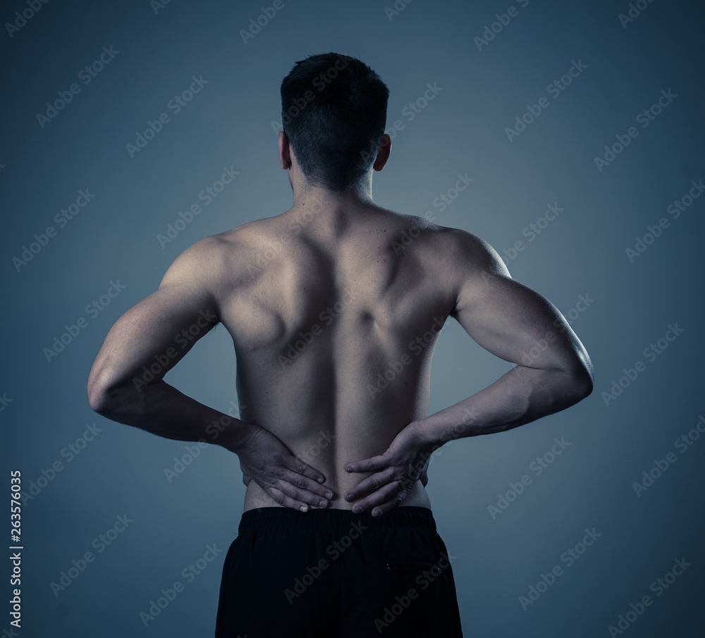 Strong young man suffering lower back pain in stress and bad posture ...