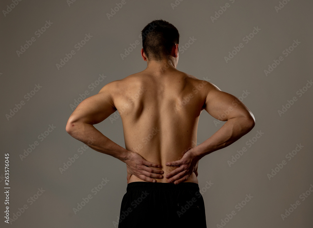 Strong young man suffering lower back pain in stress and bad posture ...
