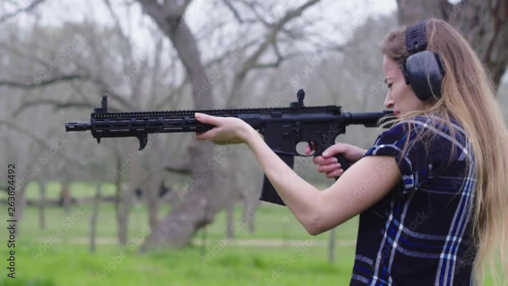 Side view of a woman getting kickback from firing a weapon during ...