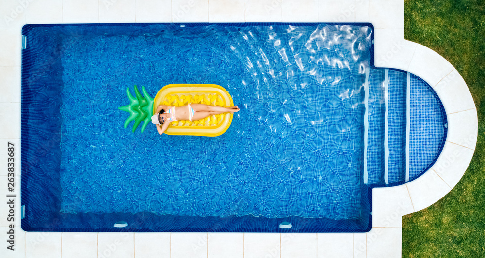 Little girl lying on a pineapple-shaped float in a swimming pool Stock ...