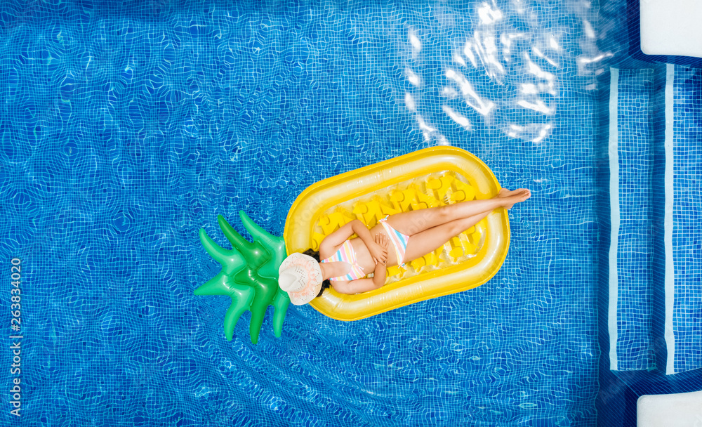 Little girl lying on a pineapple-shaped float in a swimming pool Stock ...