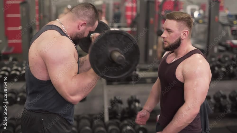 Vidéo Stock Two athletic men are working out in a gym. They are working ...