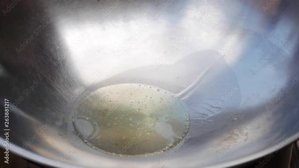 Adding vegetable oil into a wok at the beginning of a cooking process ...