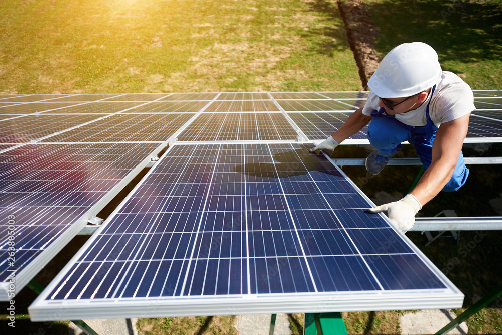 Innovative solar panels installing by young worker wearing blue uniform ...