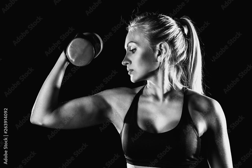 Black and white photo of a sports girl swinging biceps with a dumbbell ...