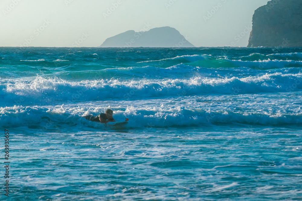 Greece, Crete, August 2018: Young man, beginner Surfer learns to surf ...