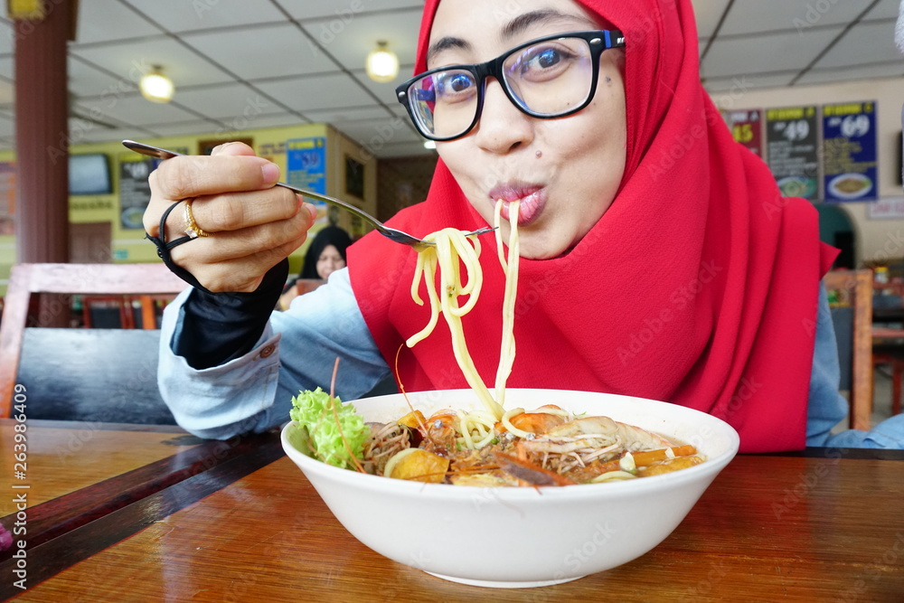 Foto de Muslim Woman enjoy eating delicious noodle or Malaysia Spicy ...