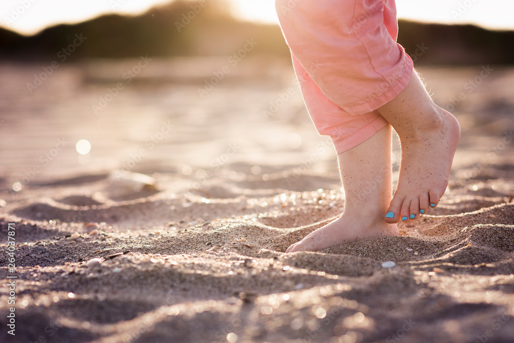Feet of little girl in sand at beach in evening light with toe nails ...
