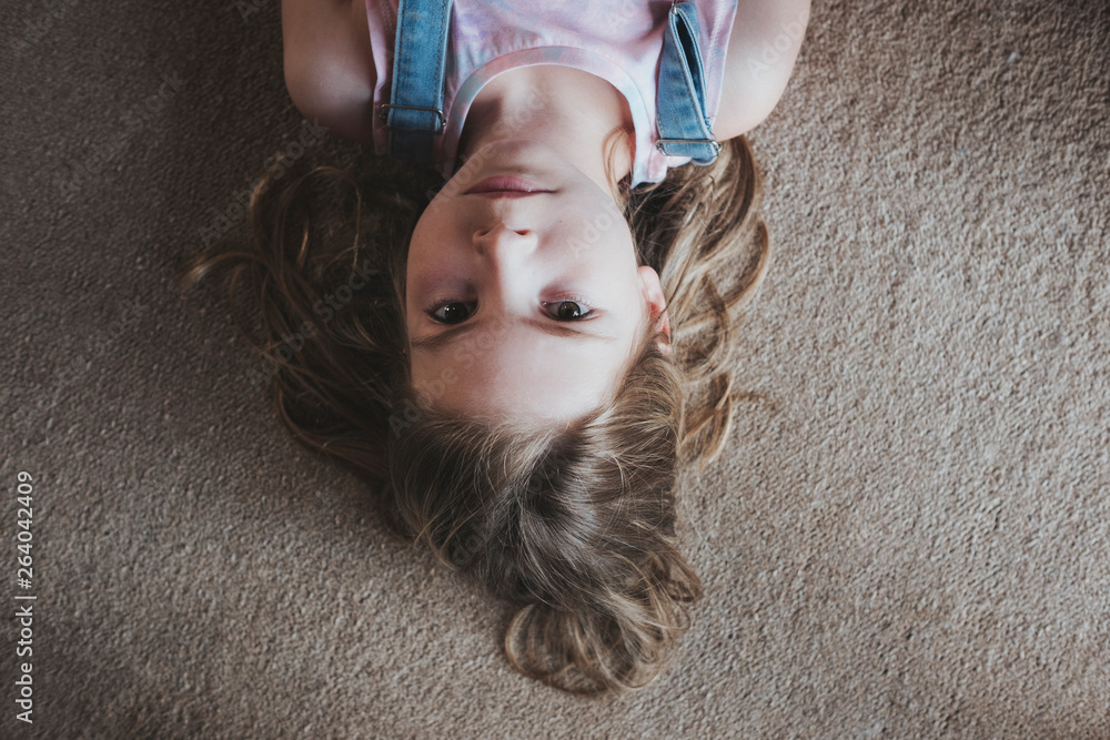 Overhead view of young girl lying on carpet floor looking up Stock ...