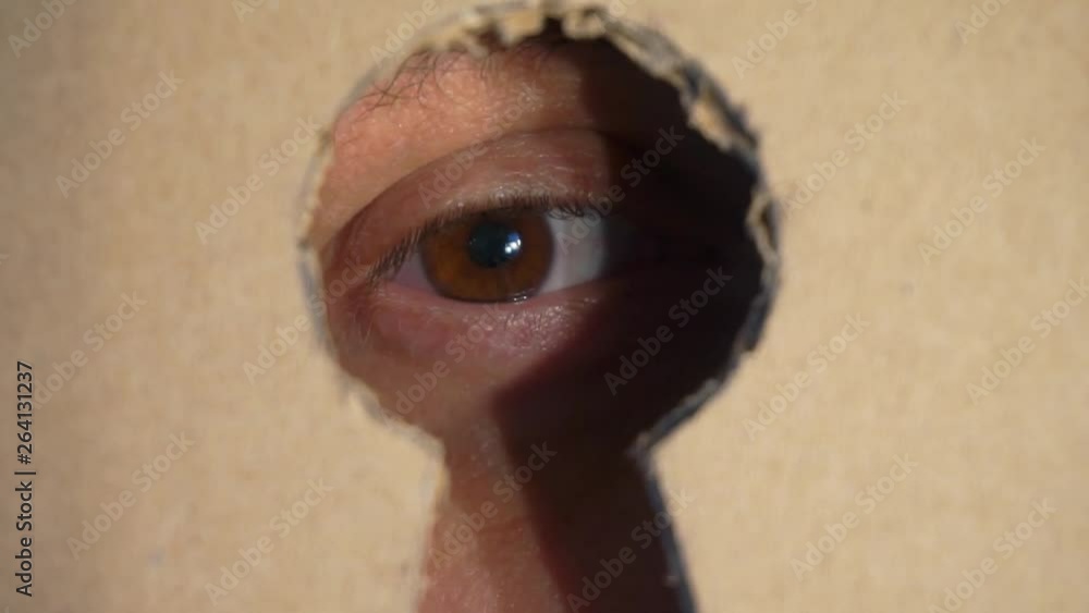curious human eye looks into the hole in the form of a keyhole.hole in ...