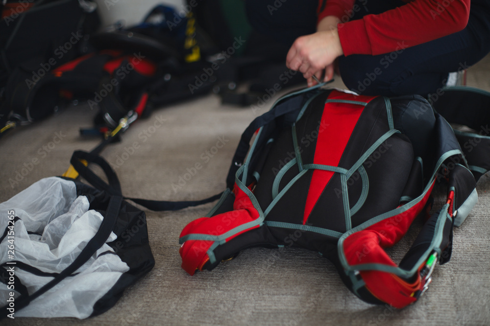 Woman rigger is packing parashute before jumping in the aerodrome room ...