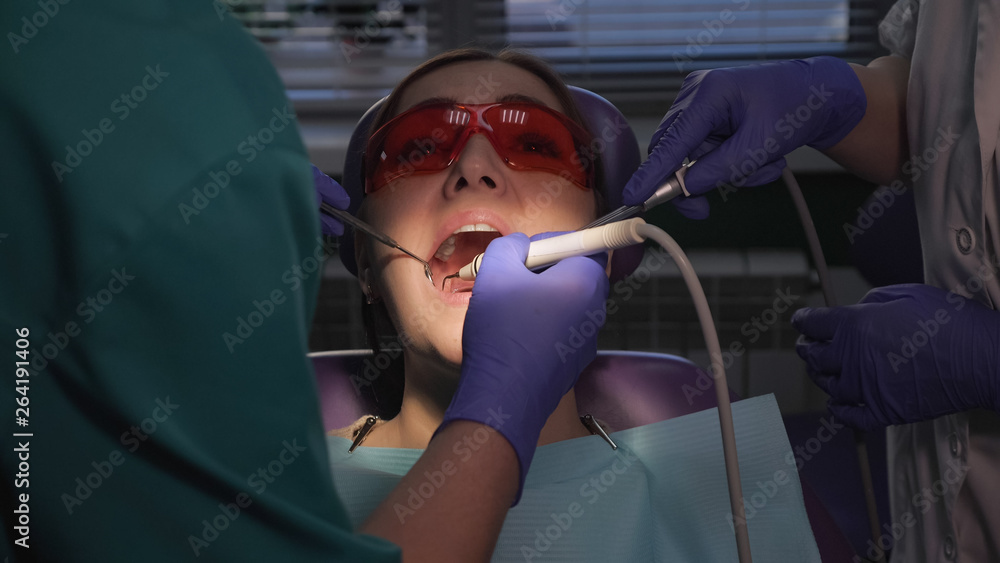 Dentist is taking care about patient's tooth using electric dental ...