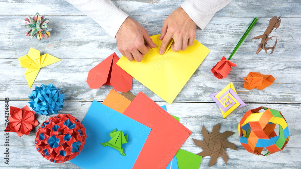 Person folding red paper sheet. Set of origami crafts made by a ...