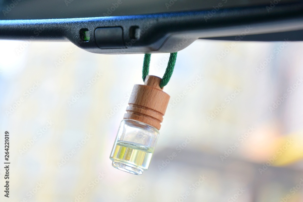 Car air perfume freshener bottle inside the car with part of car mirror ...