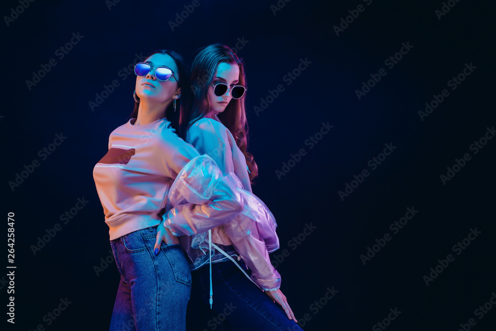 Side view of provocative teen girls in stylish jackets and sunglasses ...
