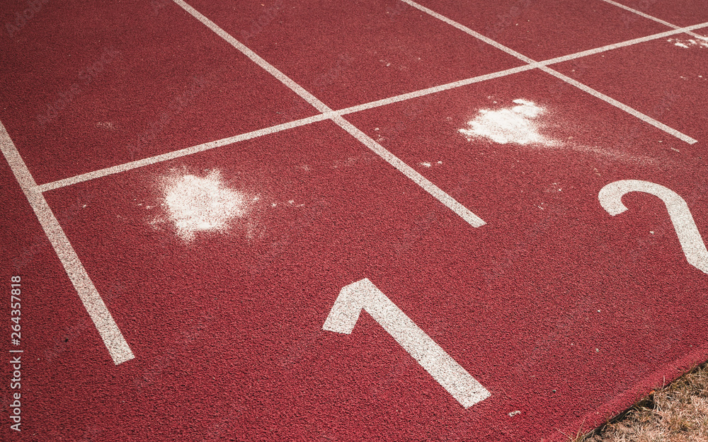 Red running track with white numbers, lines and starting line on ...