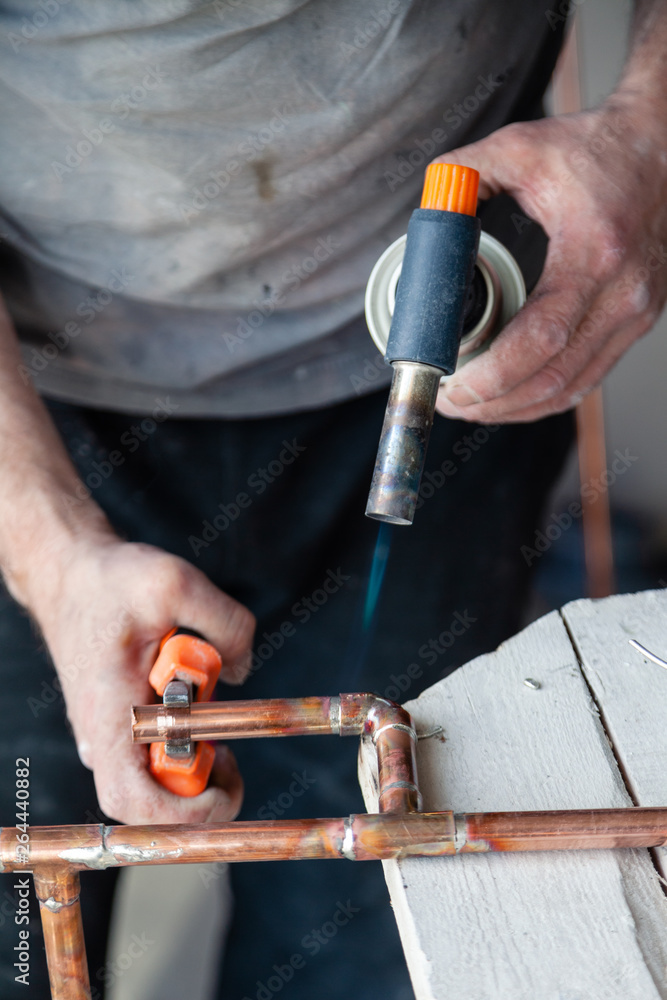 Closeup professional master plumber hands soldering copper pipes gas ...
