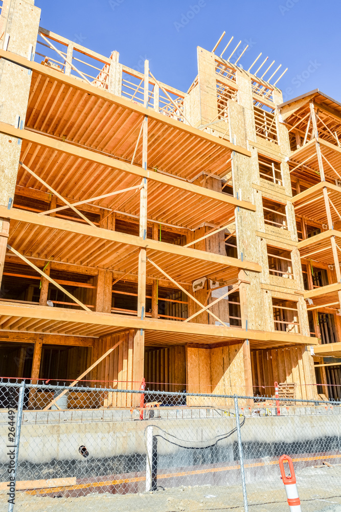 Six storey frame building under construction bordered with metal fence ...