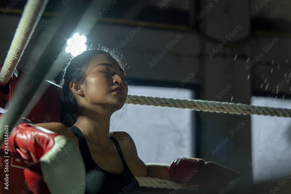Upset young fighter boxer girl wearing boxing gloves in gymมFemale ...