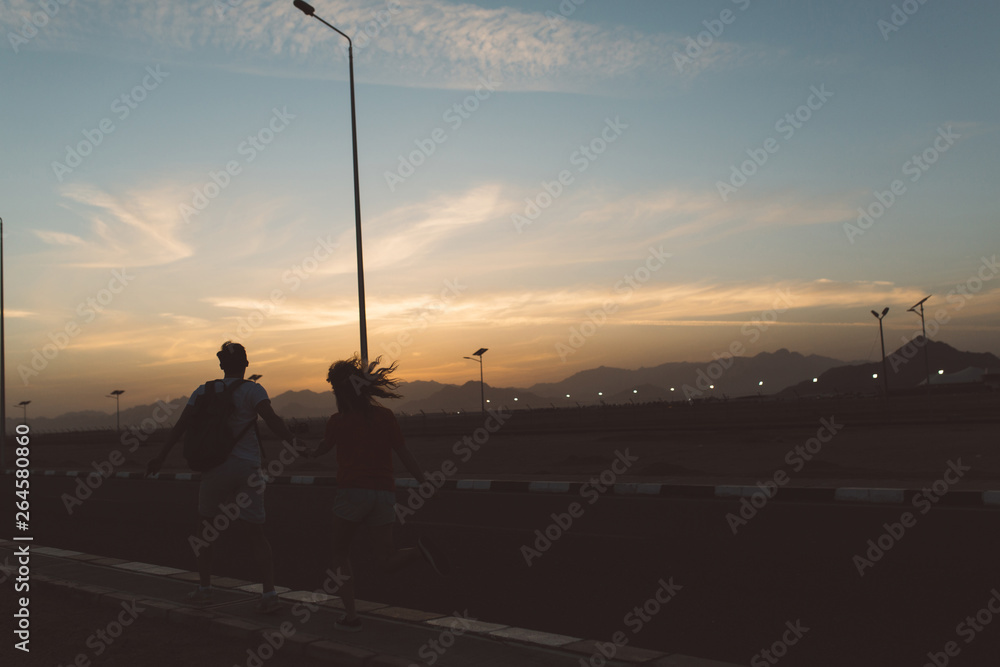 Romantic couple from back running on road on sunset background ...