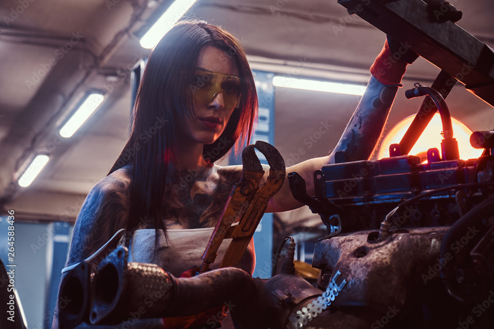 Female car mechanic holding a big hammer and posing next to a car ...