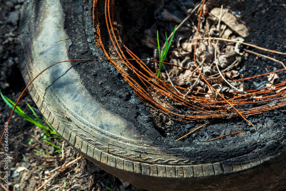 Old used dirty and burnt rubber. A rusty metal frame is visible from a ...