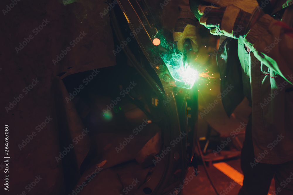 professional repairman worker in automotive industry welding metal body ...