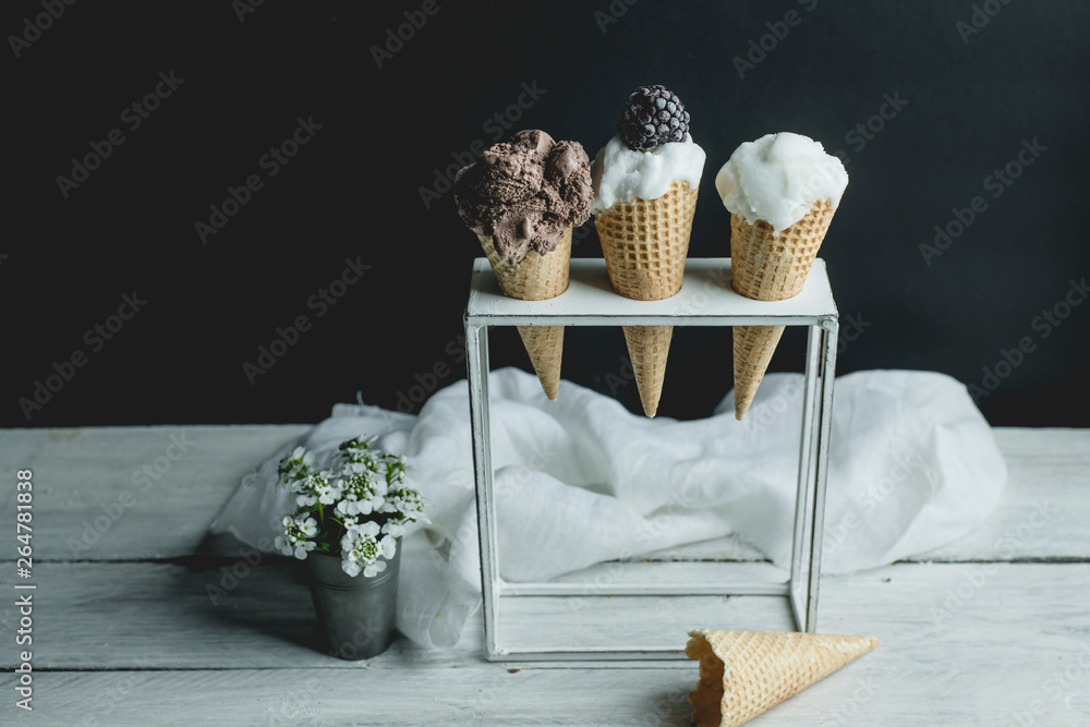 three ice cream in a wafer on a metal stand, on a dark background and ...