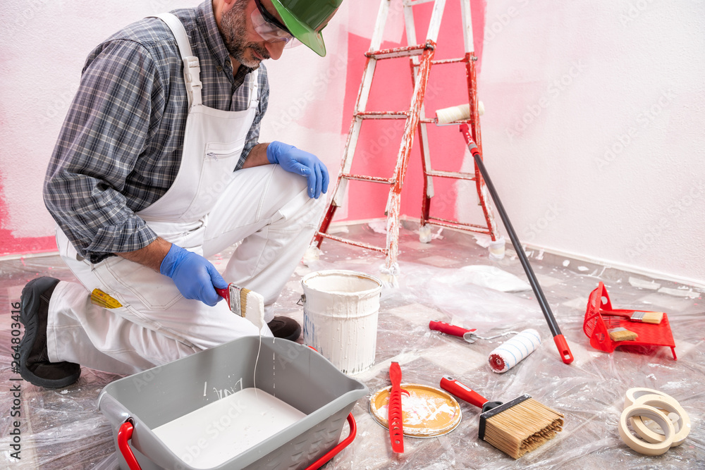 Caucasian house painter worker in white overalls, with helmet and ...