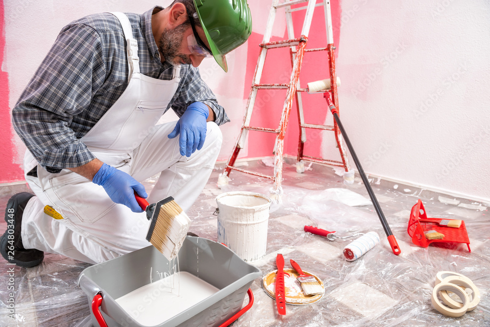Caucasian house painter worker in white overalls, with helmet and ...