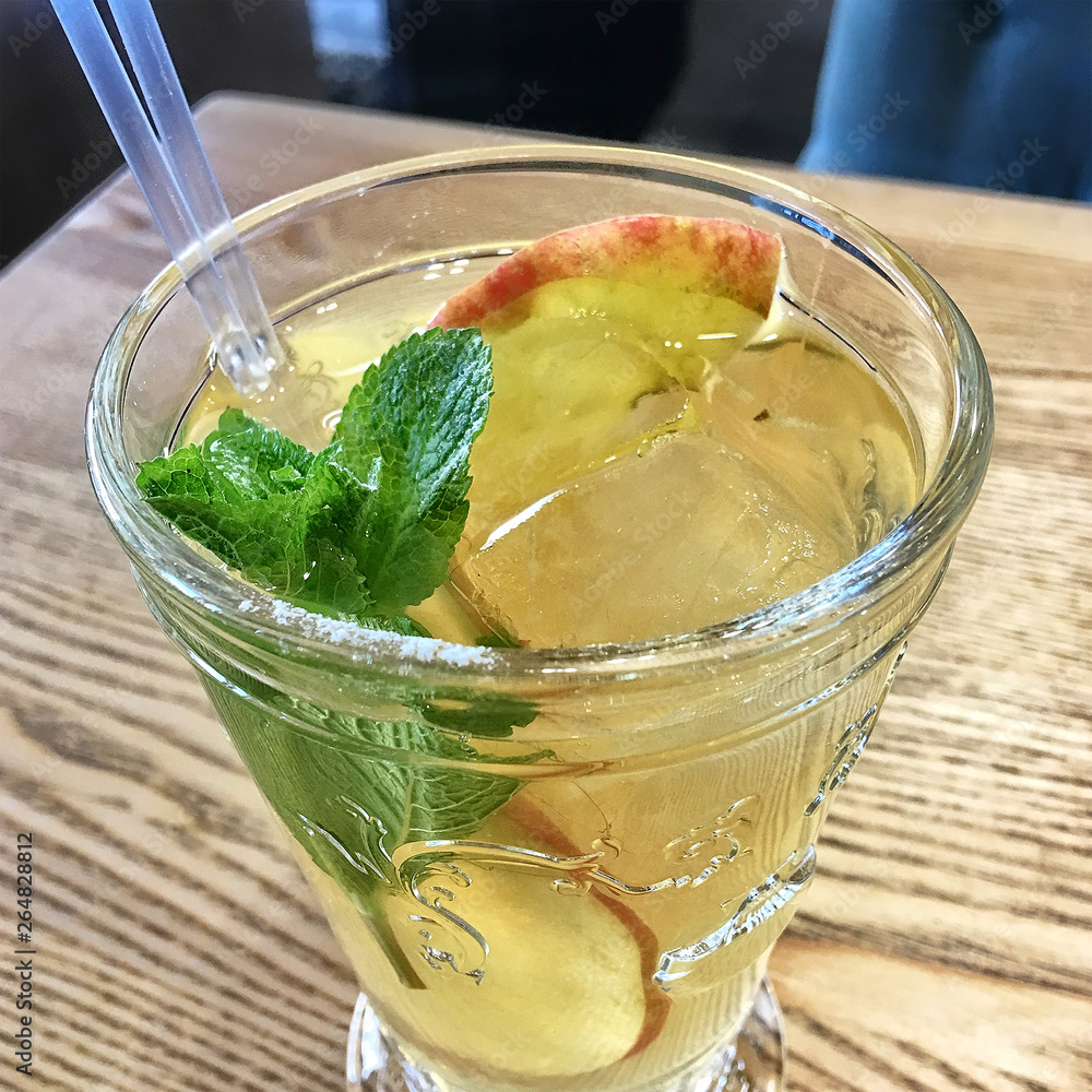Refreshing apple lemonade with ice cubes, a straw and fresh mint served ...